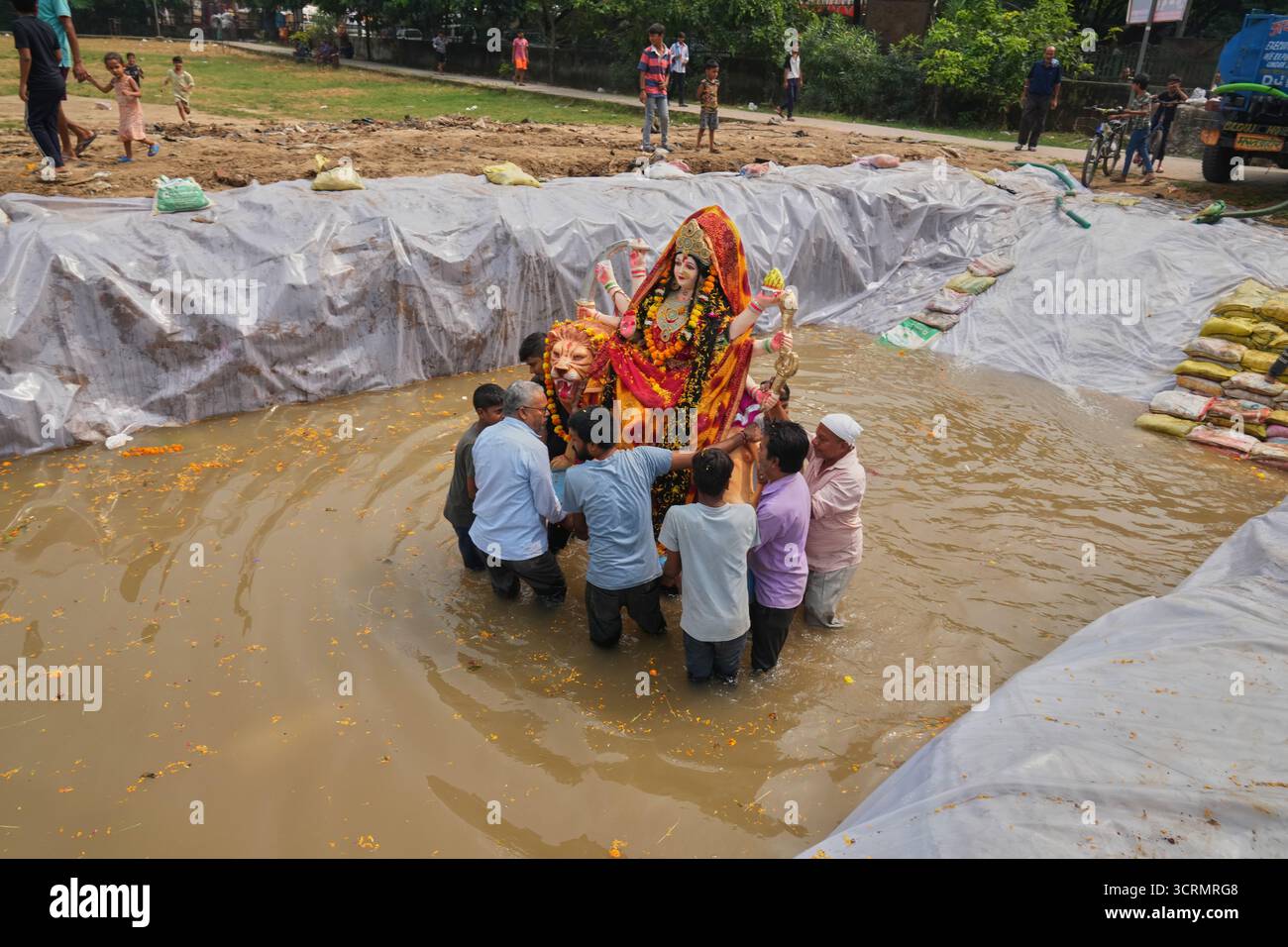 Devotees immerse an idol of Hindu goddess Durga in a makeshift water ...