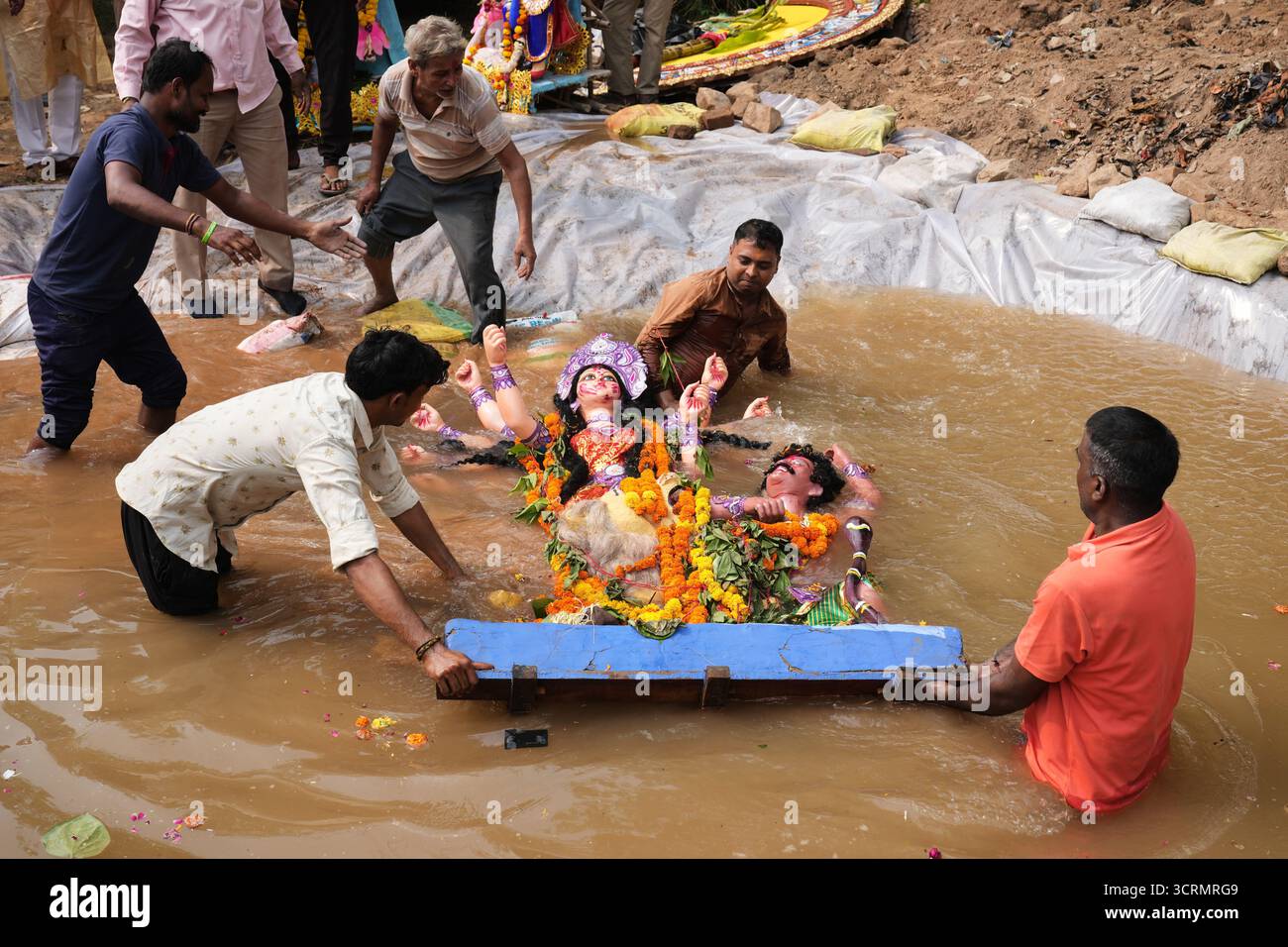 Devotees immerse an idol of Hindu goddess Durga in a makeshift water ...
