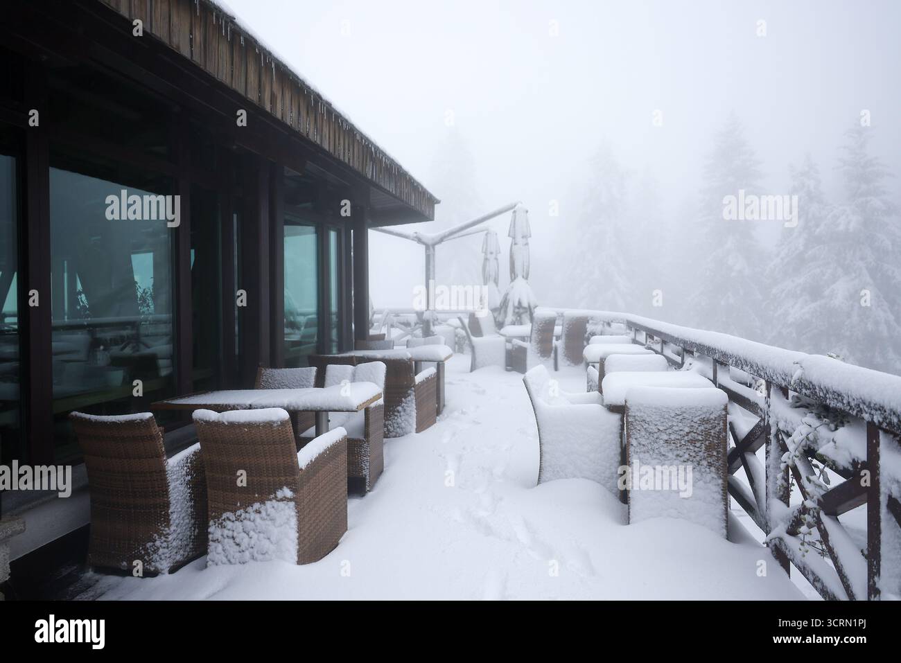 Tables and chairs on a restaurant terrace are covered with snow during an unexpected snowfall on ...