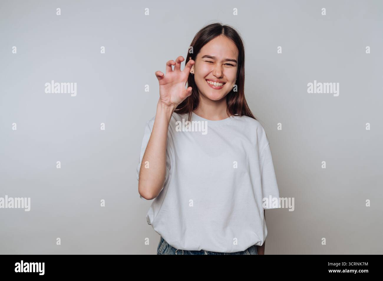 Young woman playfully making a claw gesture with her hand, smiling ...