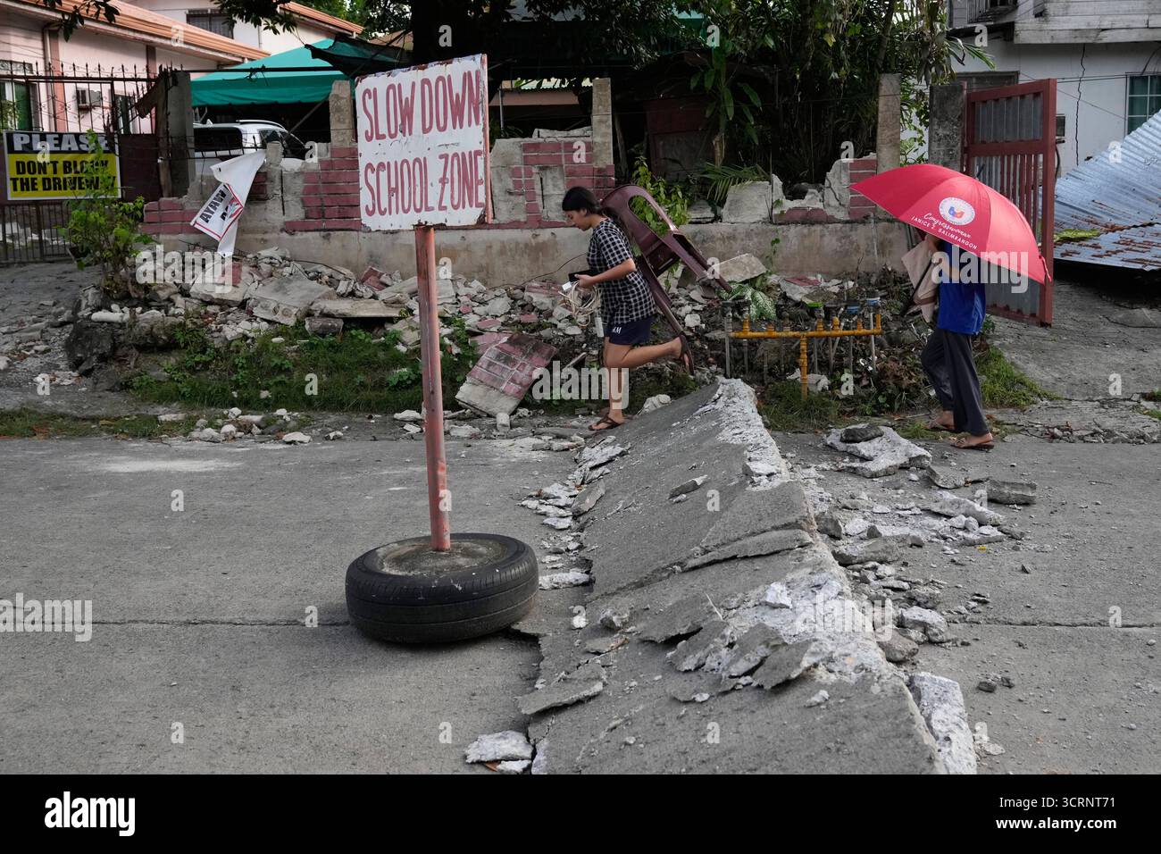 Residents walk on a damaged road caused by a recent strong earthquake ...