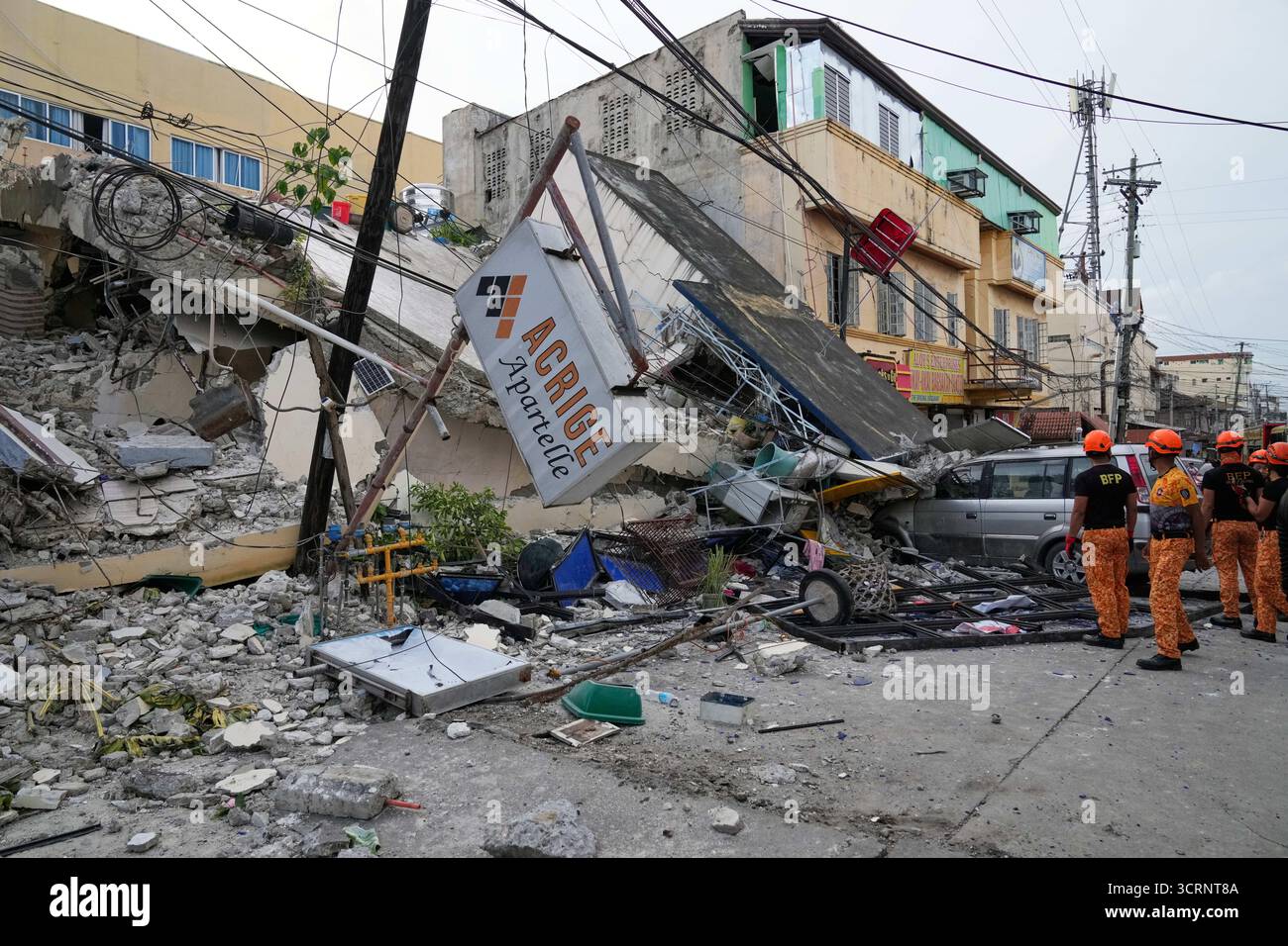 Firemen walk beside a collapsed building caused by a recent strong ...