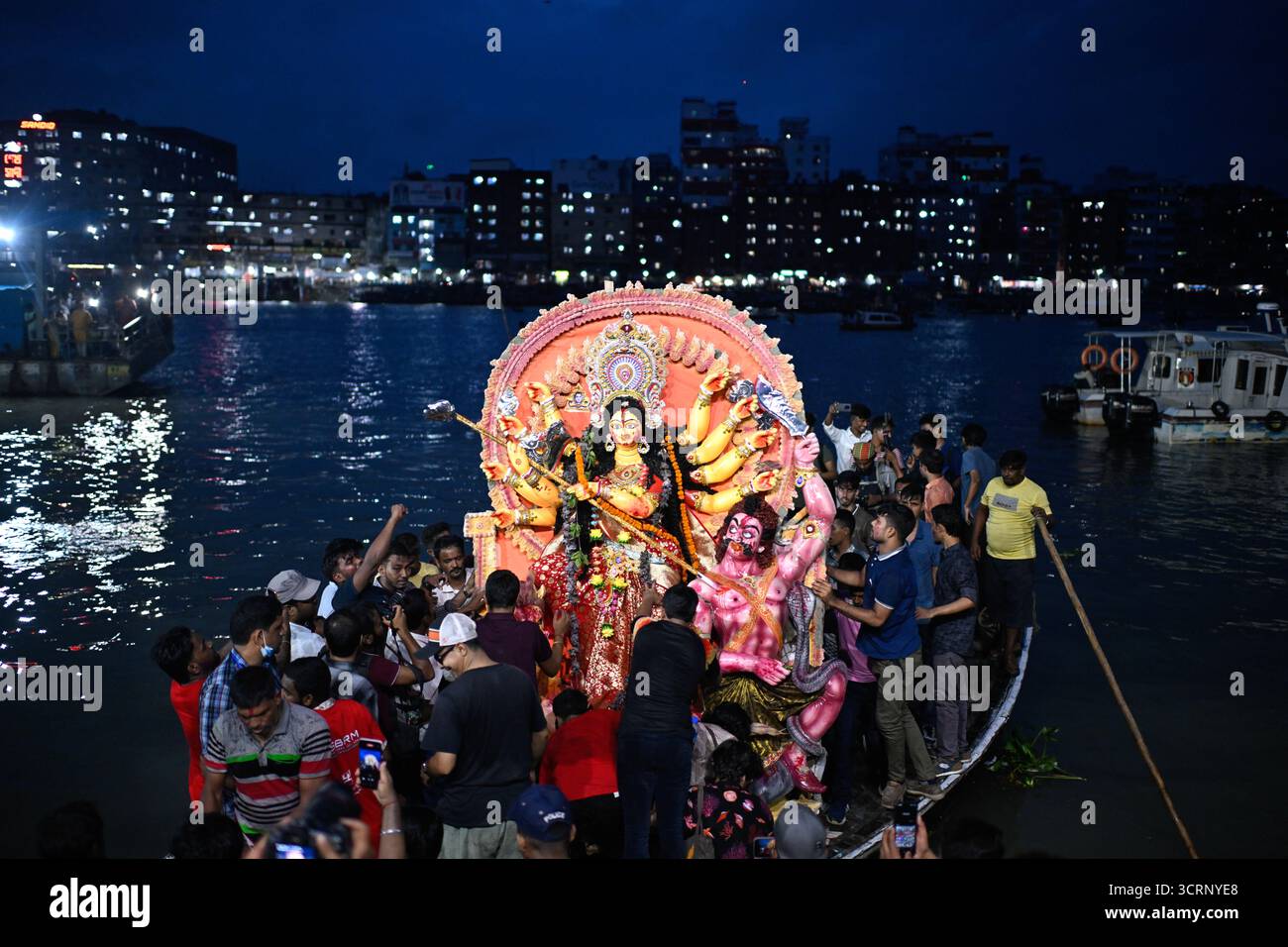 Devotees carry an idol of the Hindu goddess Durga in a boat for ...