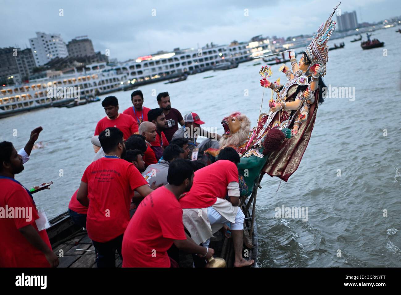 Devotees carry an idol of the Hindu goddess Durga in a boat for ...