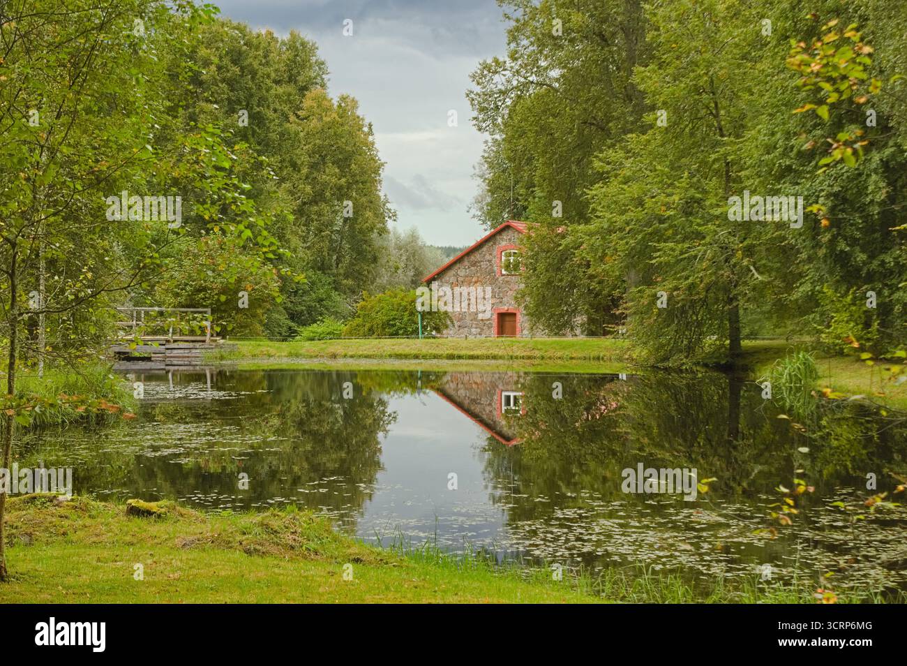 Atmospheric stone cottage from early 1900s reflected in tranquil lake ...