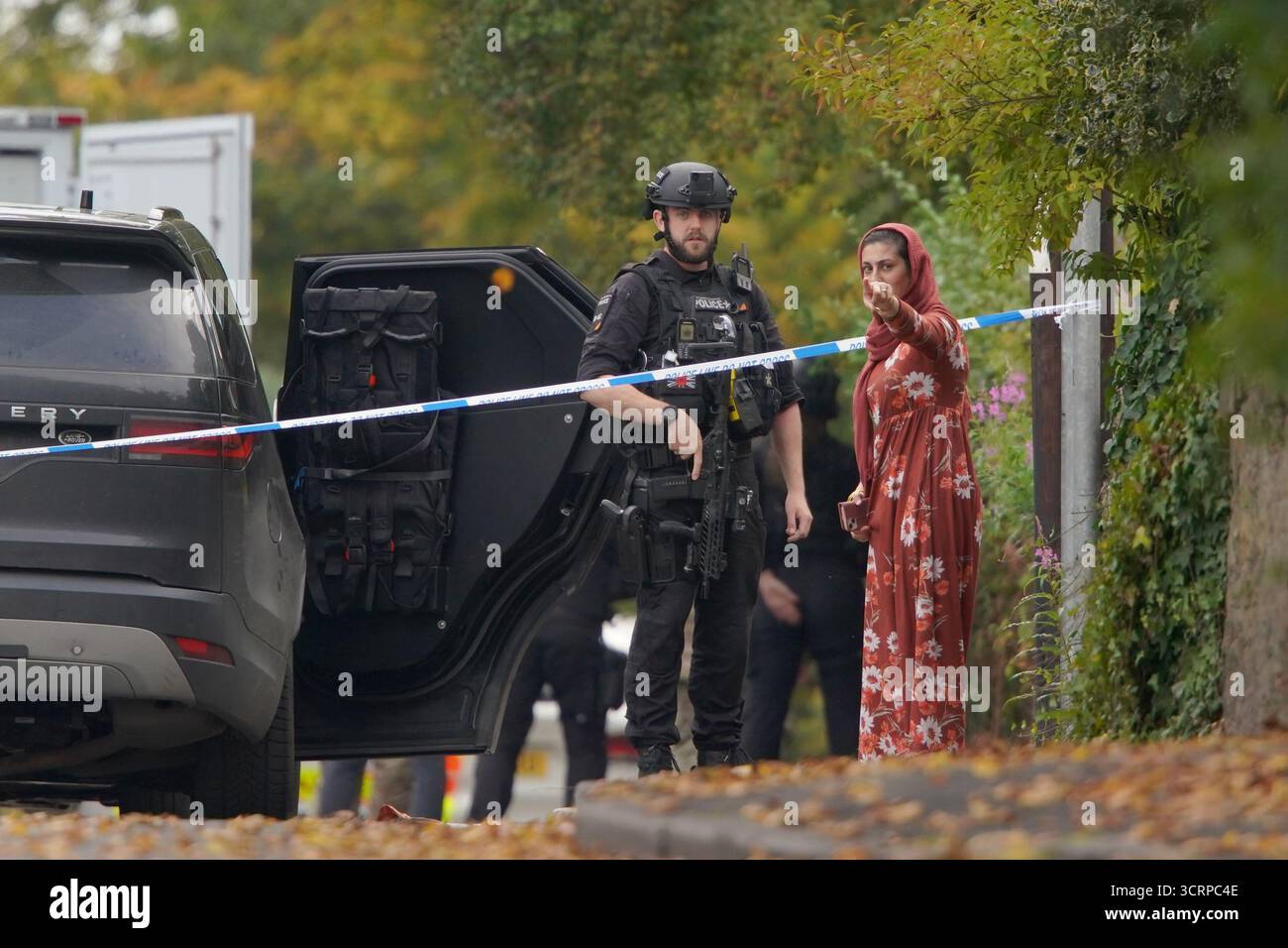 An armed police officer speaks to member of the public near the scene ...