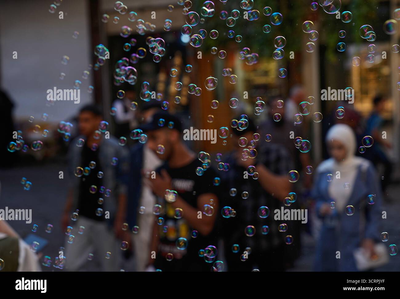 Soap bubbles float in the air as people walk through the old city of ...