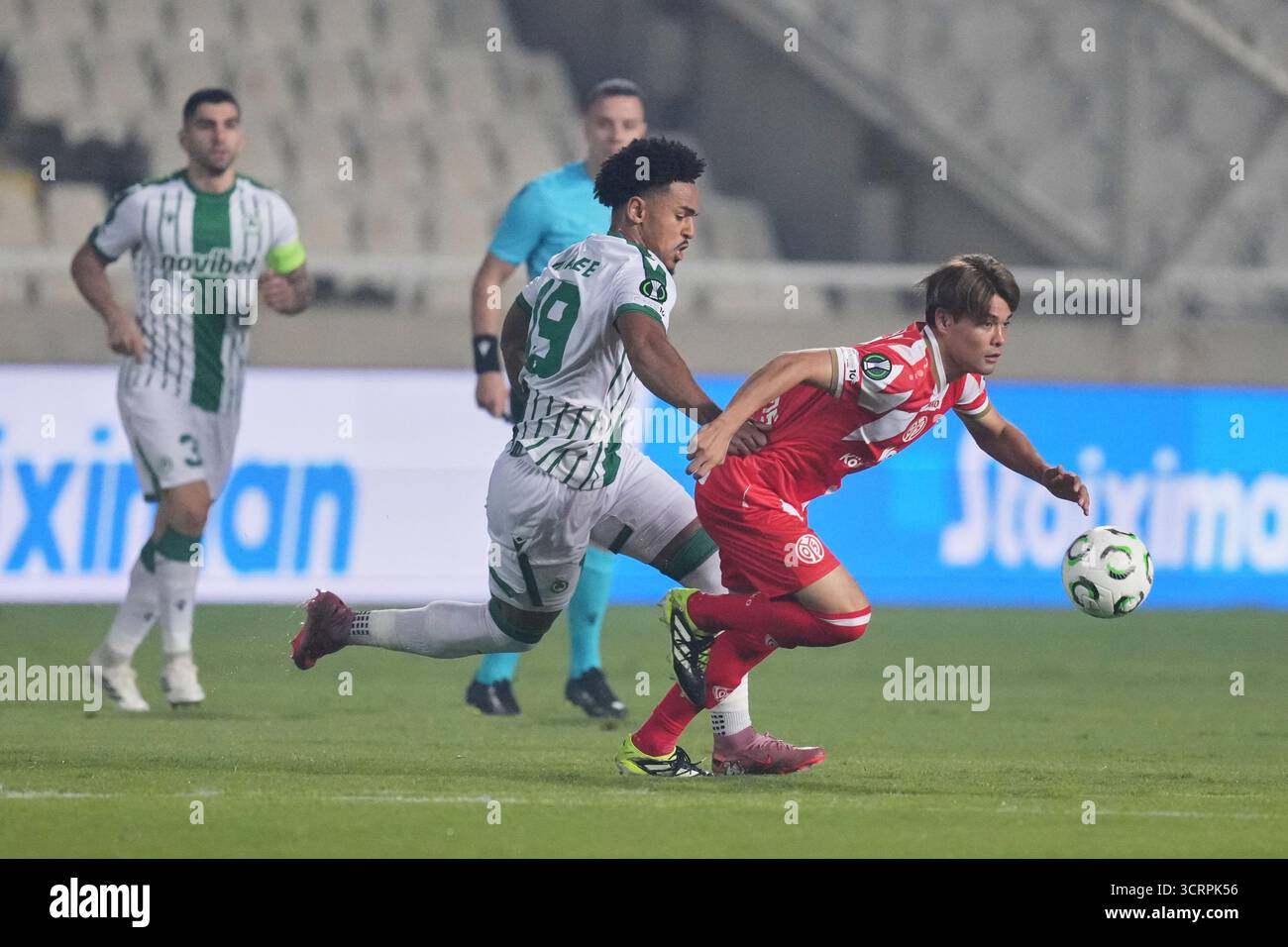 Mainz's Kaishu Sano, right, is challenged by Omonoia's Ryan Mmaee ...