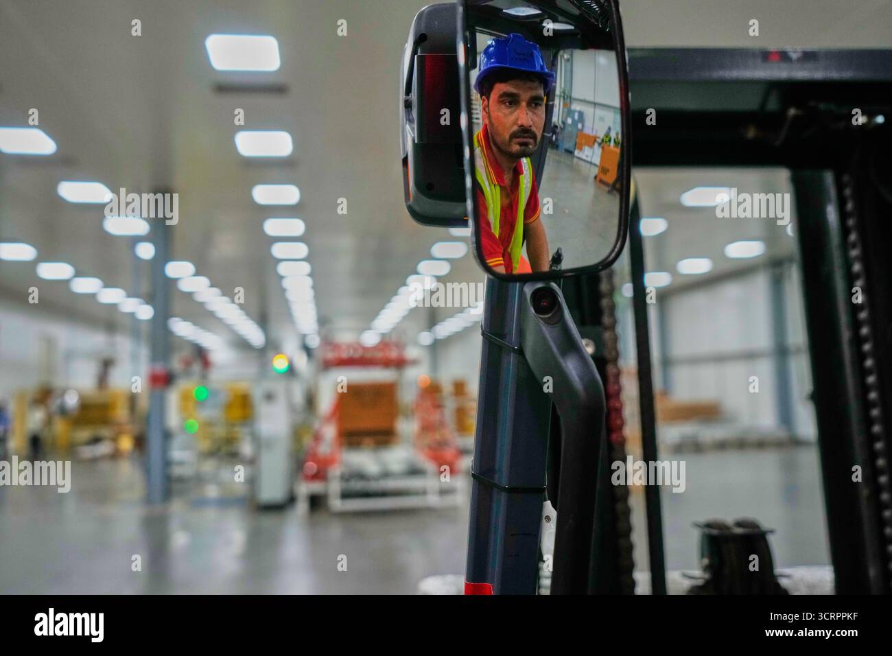 A worker waits in his forklift machine to lift solar panel for packing ...