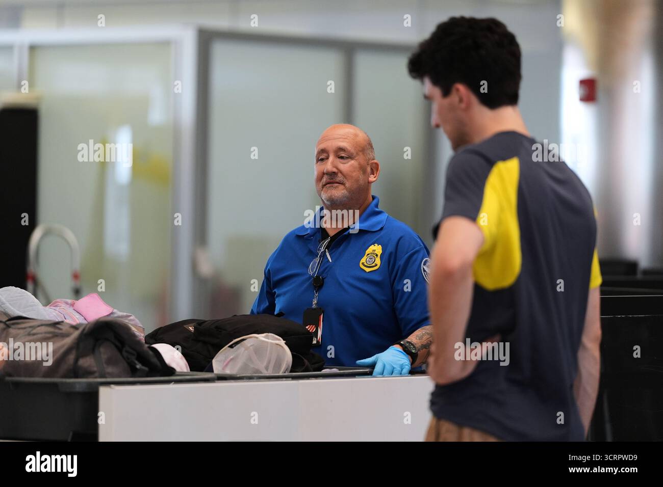 A Transportation Security Administration agent, left, works at a ...