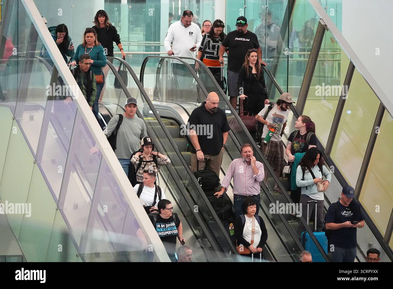 Travelers descend on escalators after passing through the west security ...