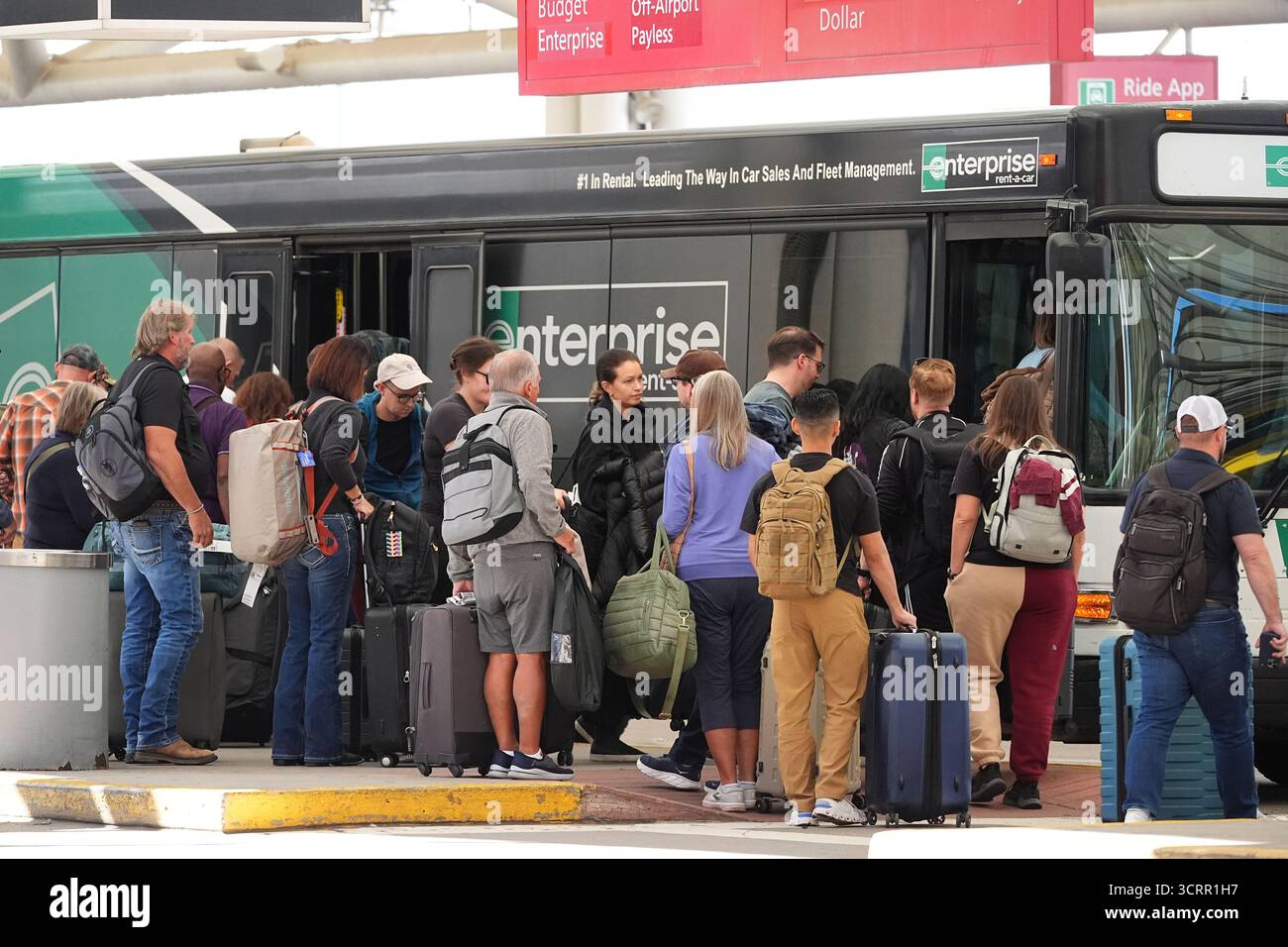 Travelers crowd to enter a shuttle bus to the rental car lot outside ...