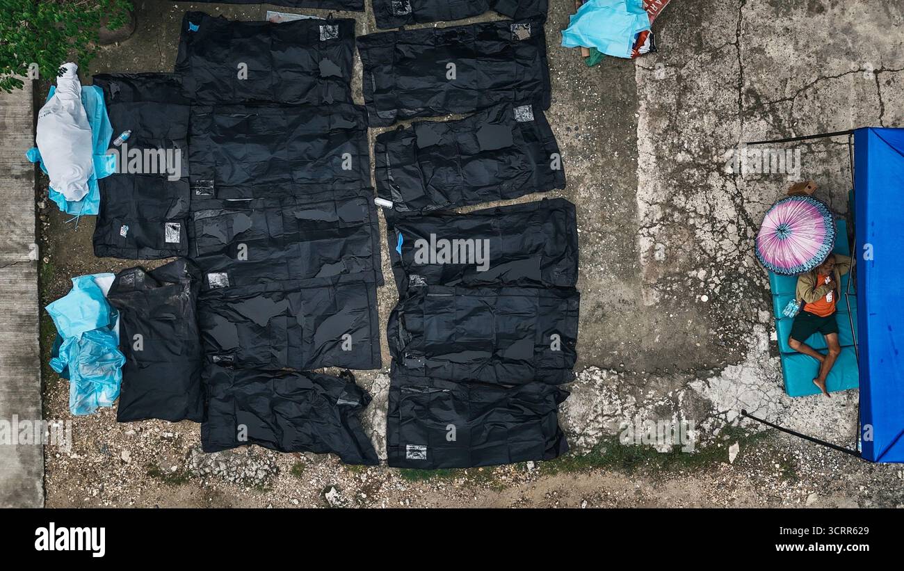 A man rests beside bodies of victims of an earthquake outside Cebu ...