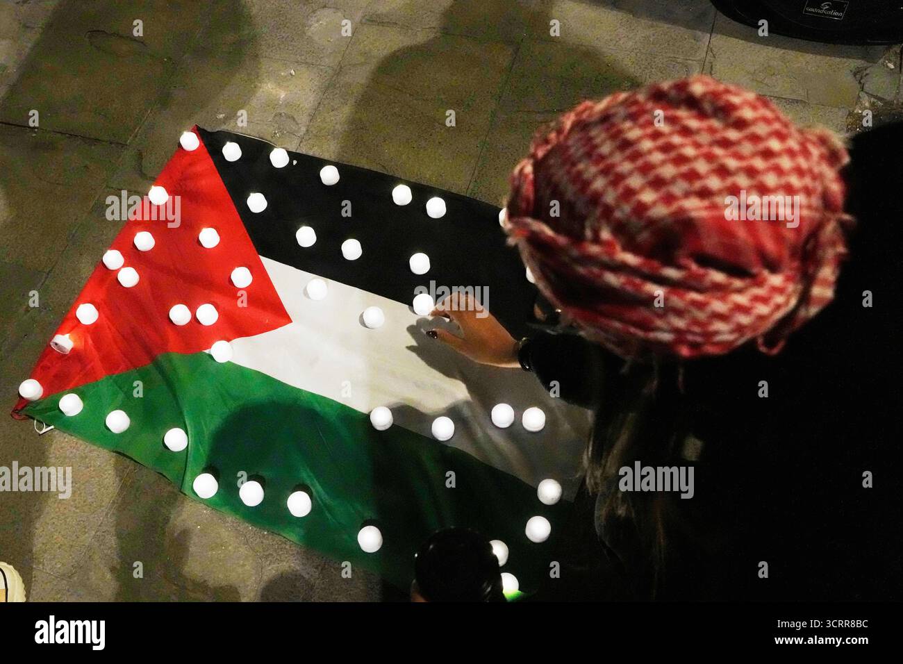 A woman places candles over a Palestinian flag as doctors and nurses ...