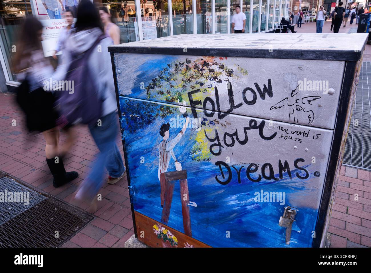 Pedestrians walk past a inspirational painting, stating "Follow your ...