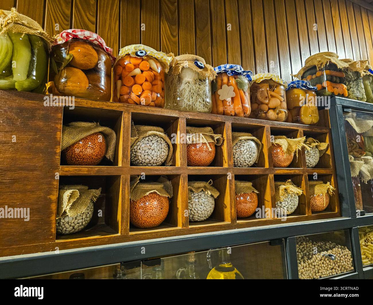 Rustic wooden shelf with glass jars of pickled vegetables, legumes, and ...