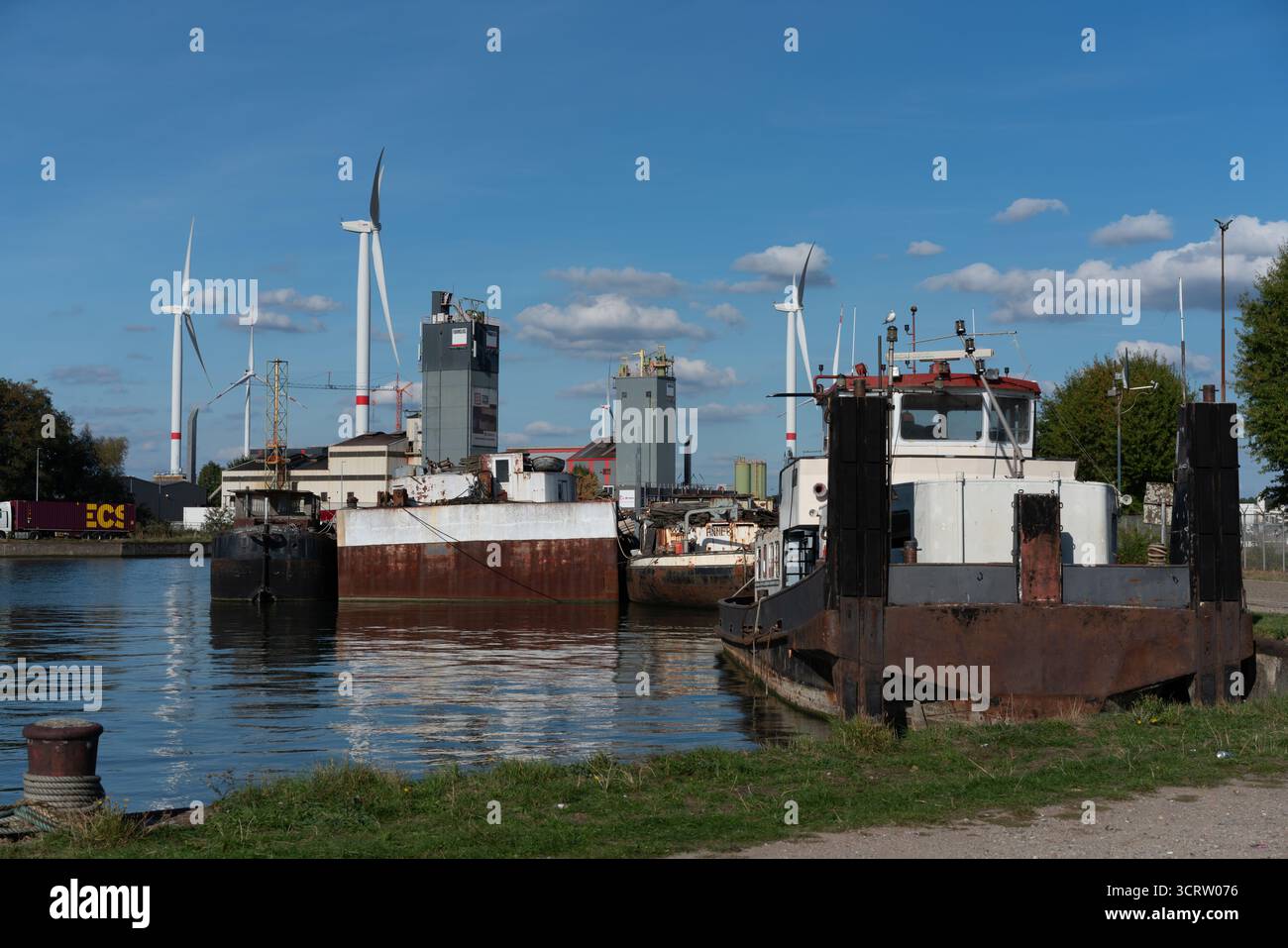 Barges, boats, and industrial facilities with wind turbines along the ...