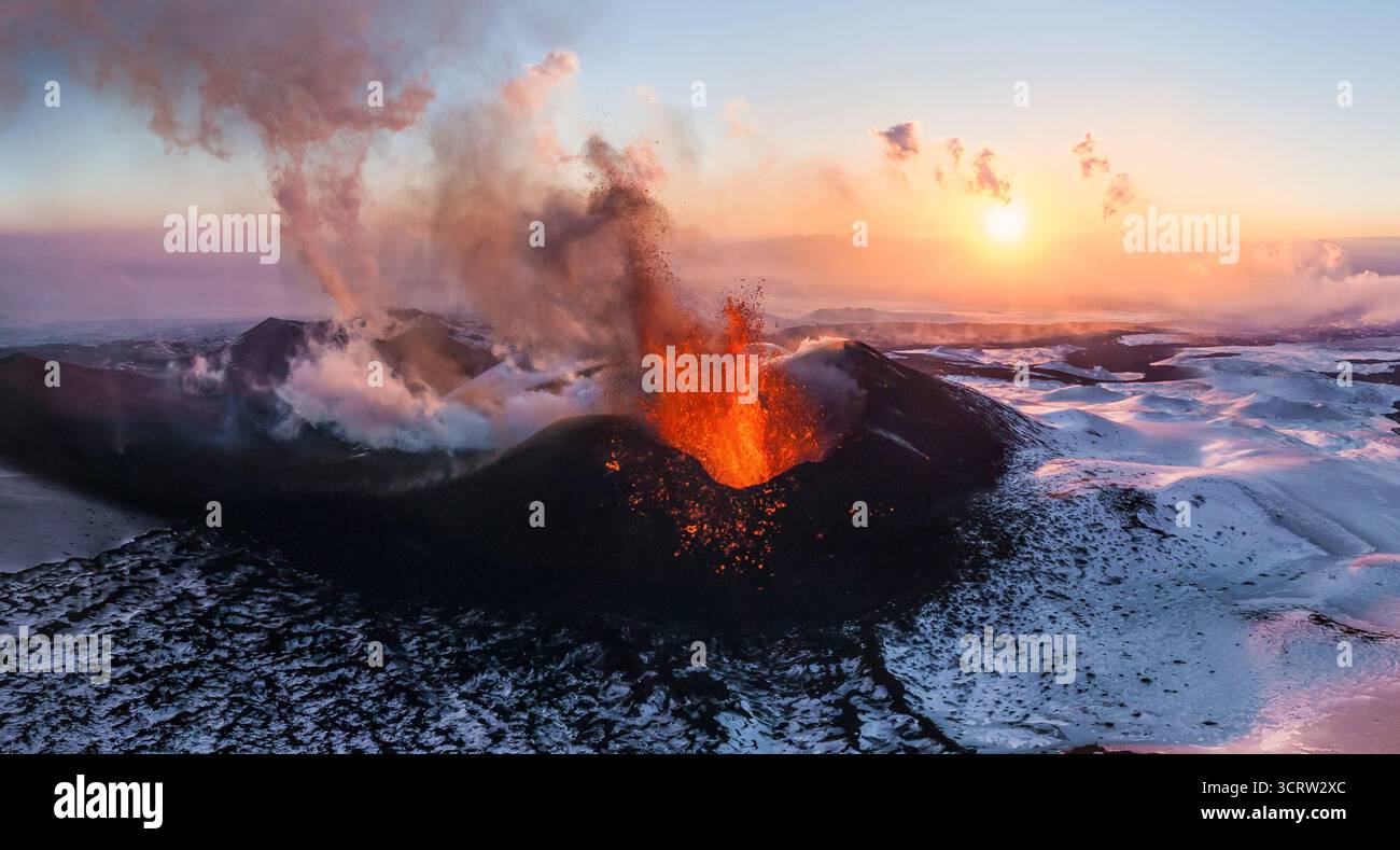Aerial view of fiery lava erupting from a volcano amid a landscape of ...