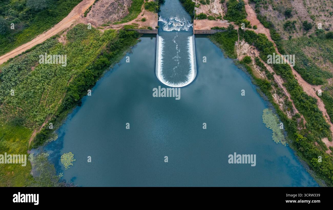 Aerial view of water cascading over a dam into a tranquil reservoir ...