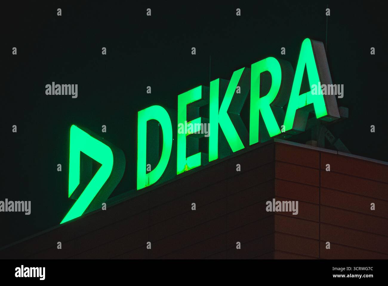 DEKRA brand logo signboard on the office building rooftop glowing green ...