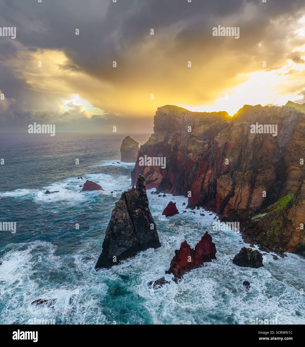 Aerial view of jagged cliffs meet the tumultuous sea under a dramatic ...