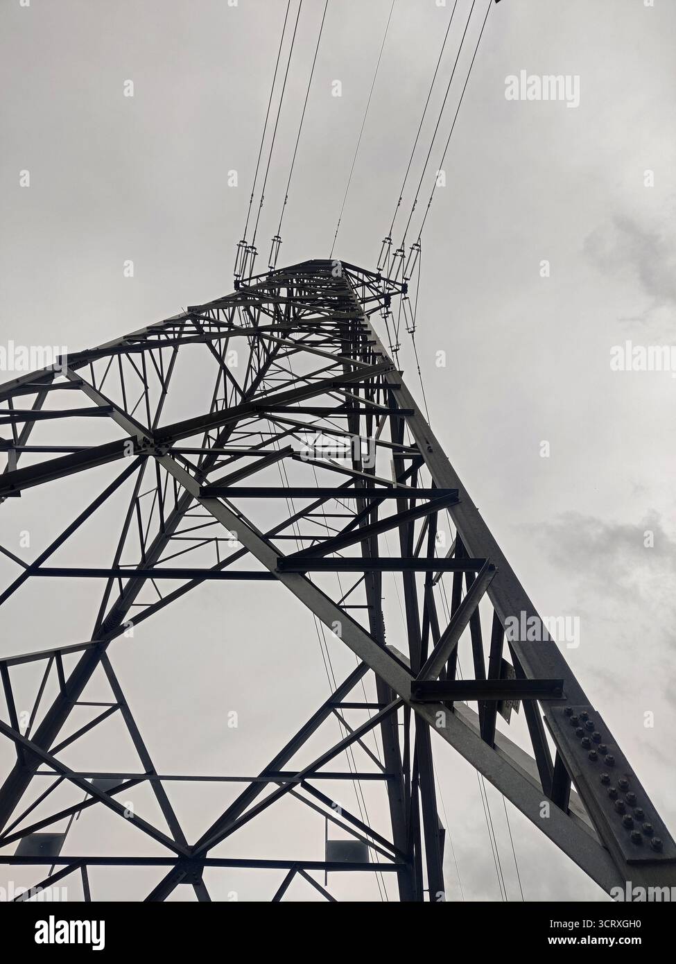 Steel power transmission tower against cloudy sky. A low-angle view of ...