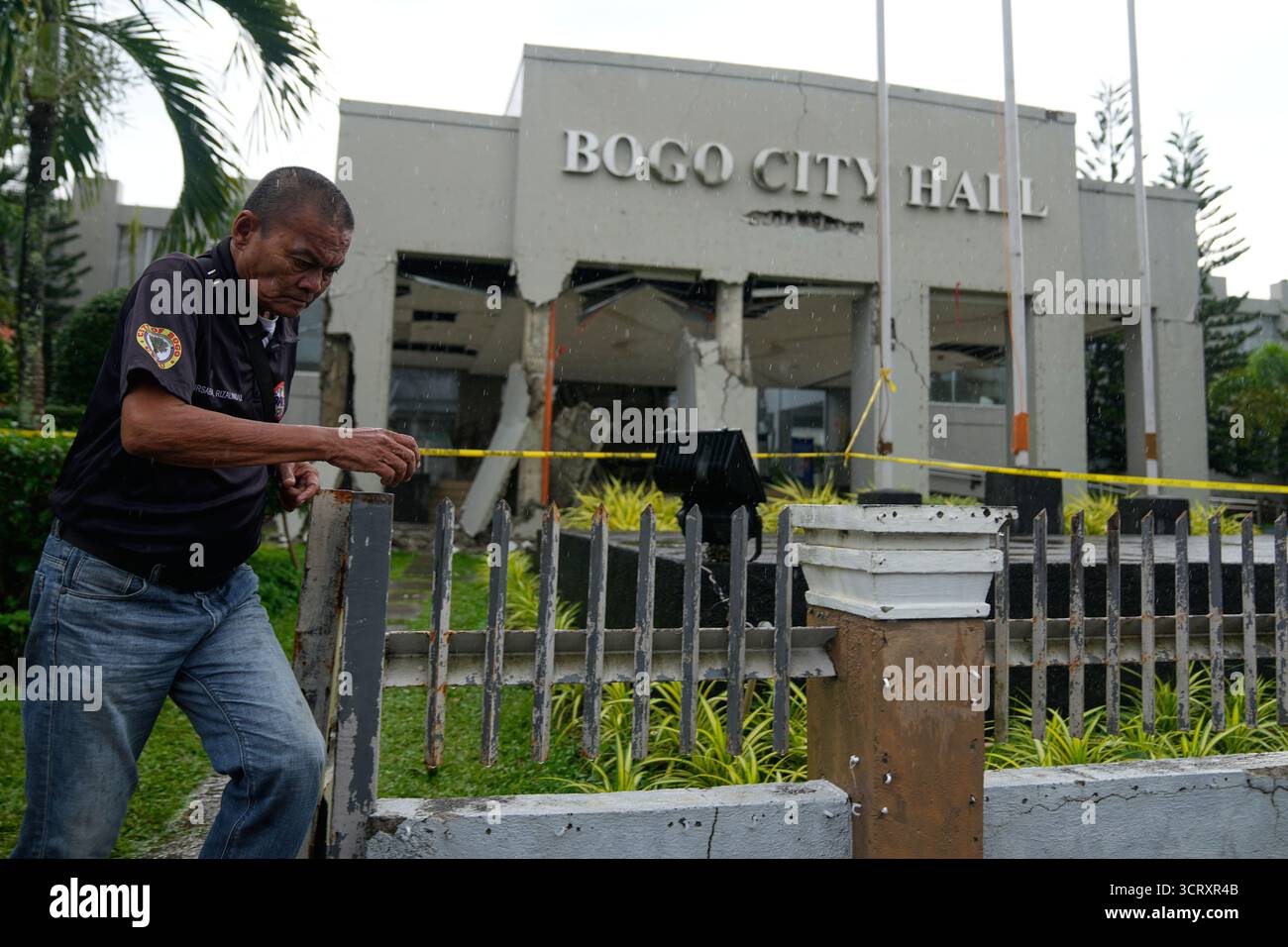 A man passes by the earthquake damaged Bogo City Hall building, in Cebu ...