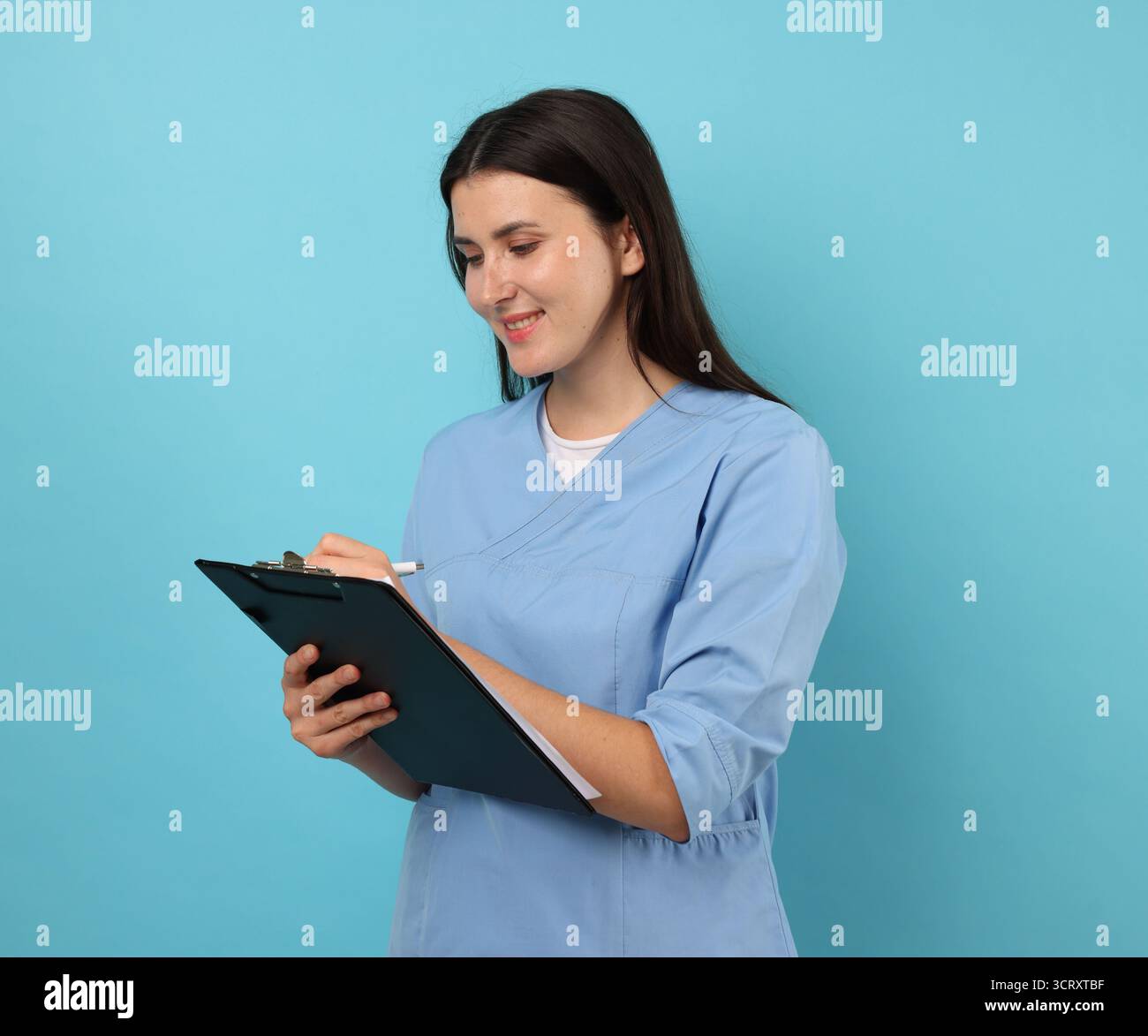 Nurse with clipboard taking notes on light blue background Stock Photo ...