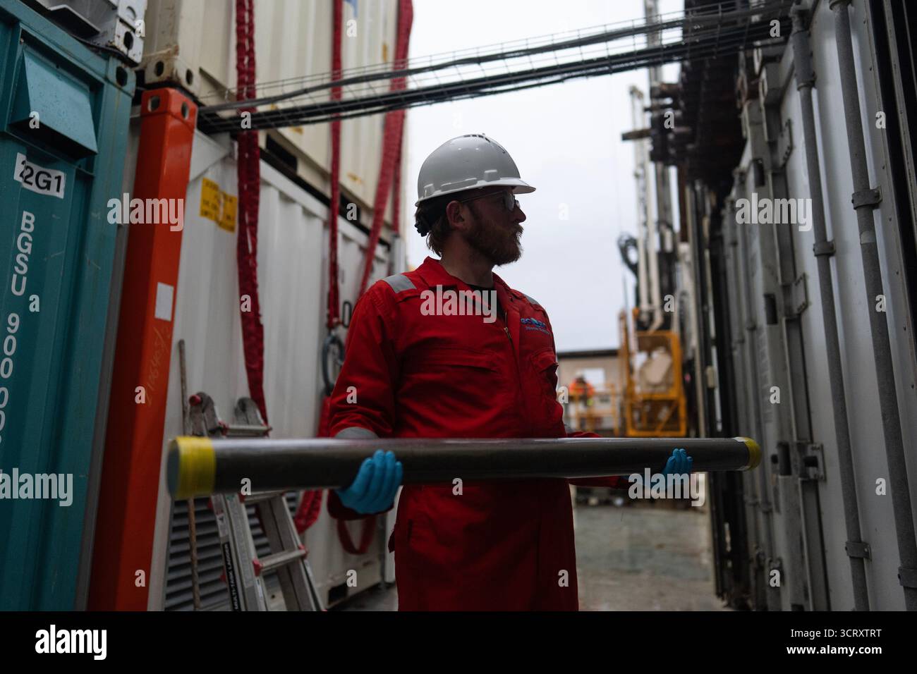 Expedition 501 researcher Jack Brickell carries a core to a cold ...