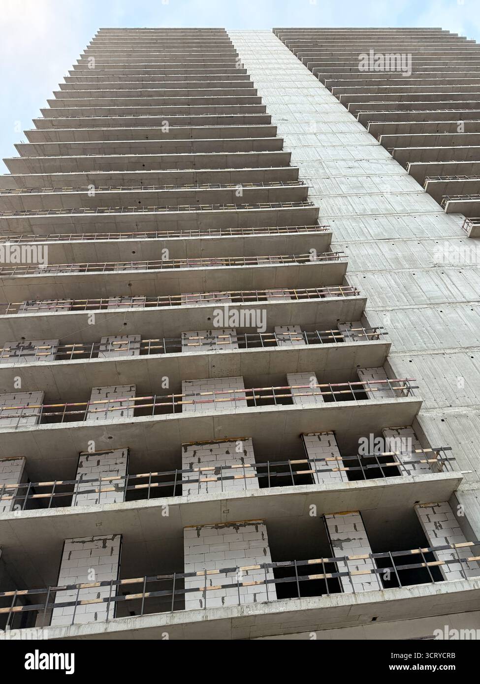 The image shows a tall reinforced concrete building under construction ...