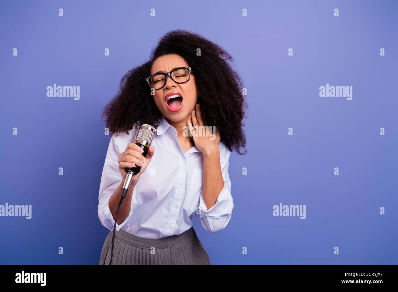Young woman passionately singing into a microphone against a vibrant ...