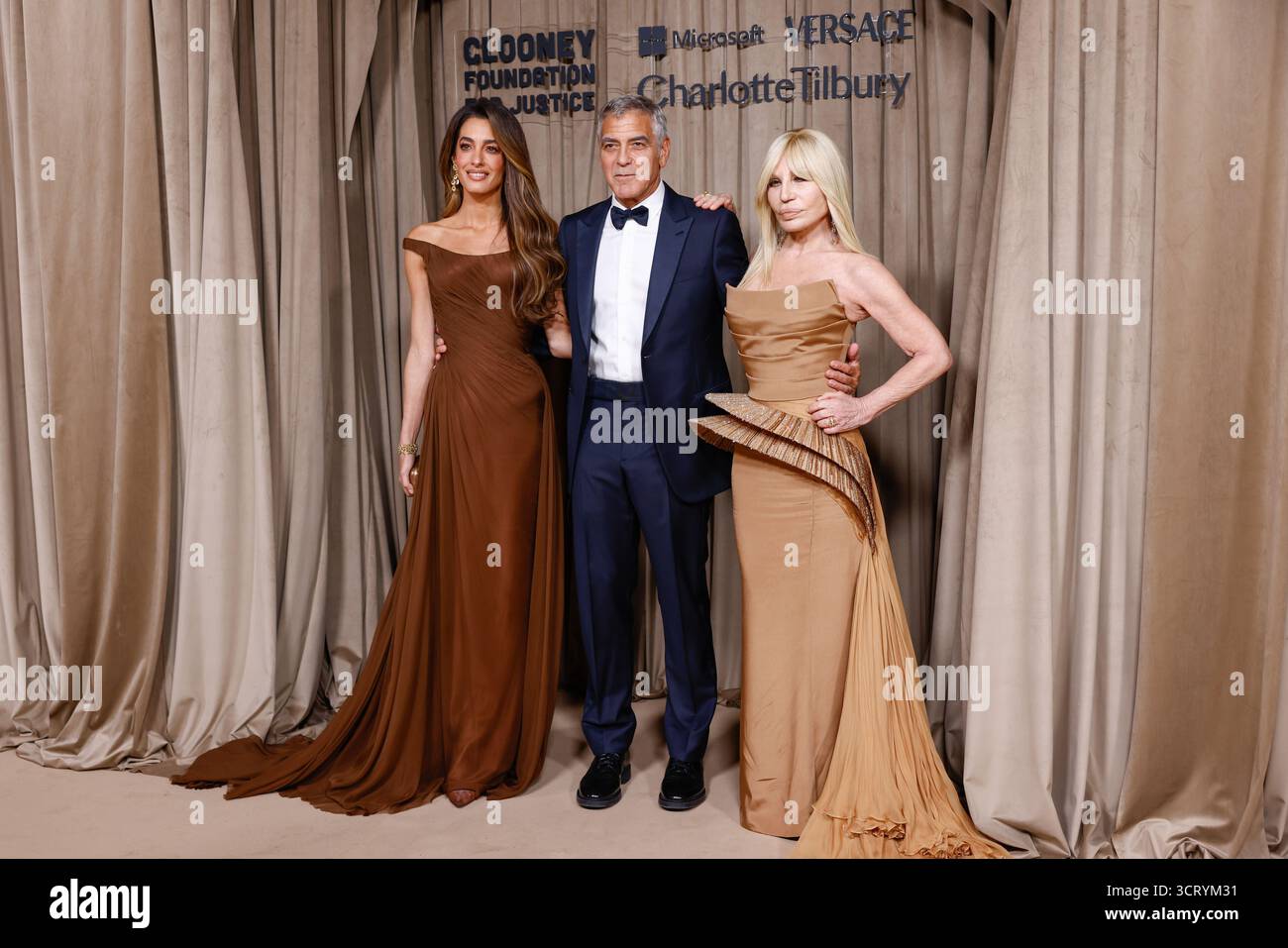 Amal Clooney, from left, George Clooney, and Donatella Versace pose for photographers upon ...