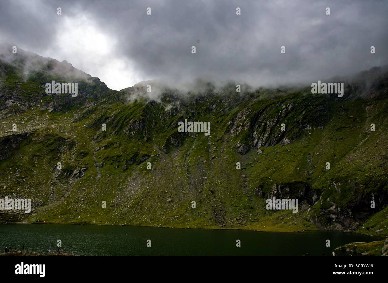 Dark Glacial Lake and Steep Green Alpine Slopes under Stormy Sky Stock ...