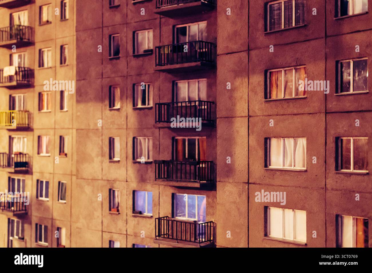 Colorful night view of a concrete apartment block with glowing windows ...