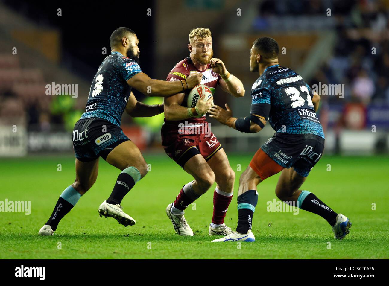 Wigan Warriors' Luke Thompson (centre) is tackled by Leigh Leopards ...