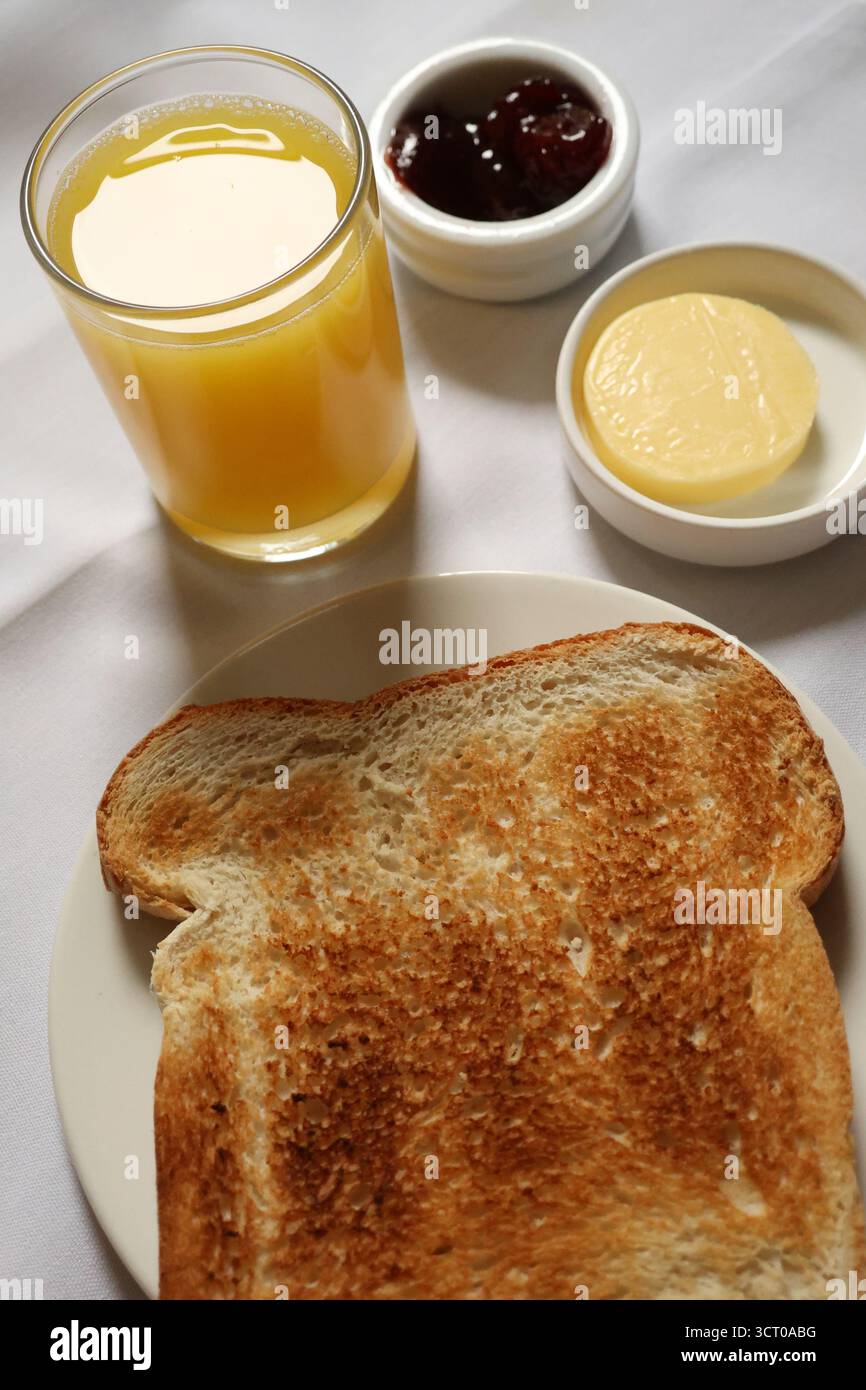 Breakfast setup presenting plain toasted bread, orange juice ...