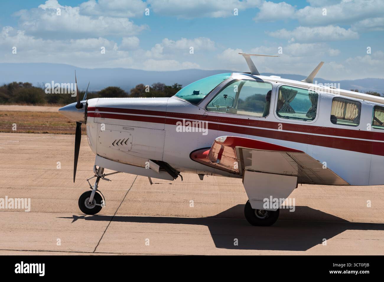 small plane taking off the runway airport strip, blue sky and bush in ...