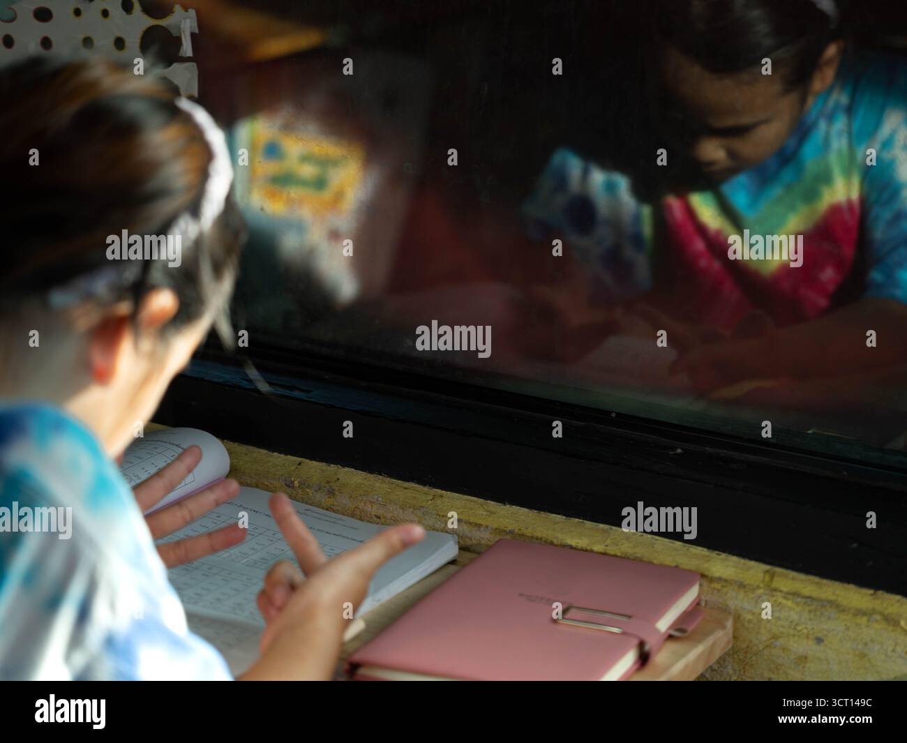 Asian girl studying math at a desk, counting numbers with her fingers ...
