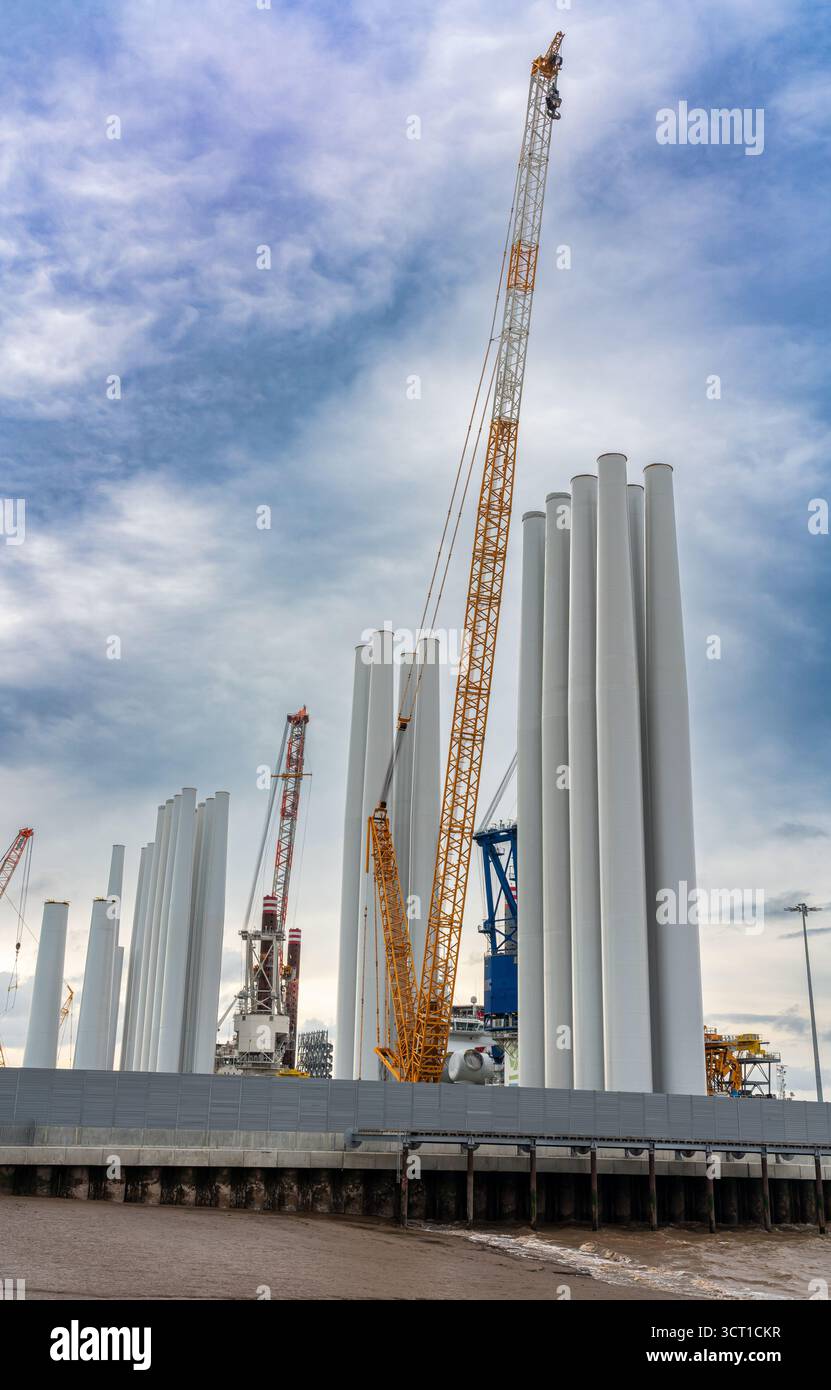 Cranes and turbine tower sections at an offshore wind turbine assembly ...