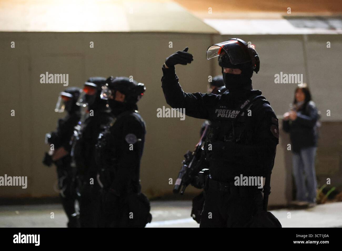 A Portland Police officer waves a vehicle through as people protest ...