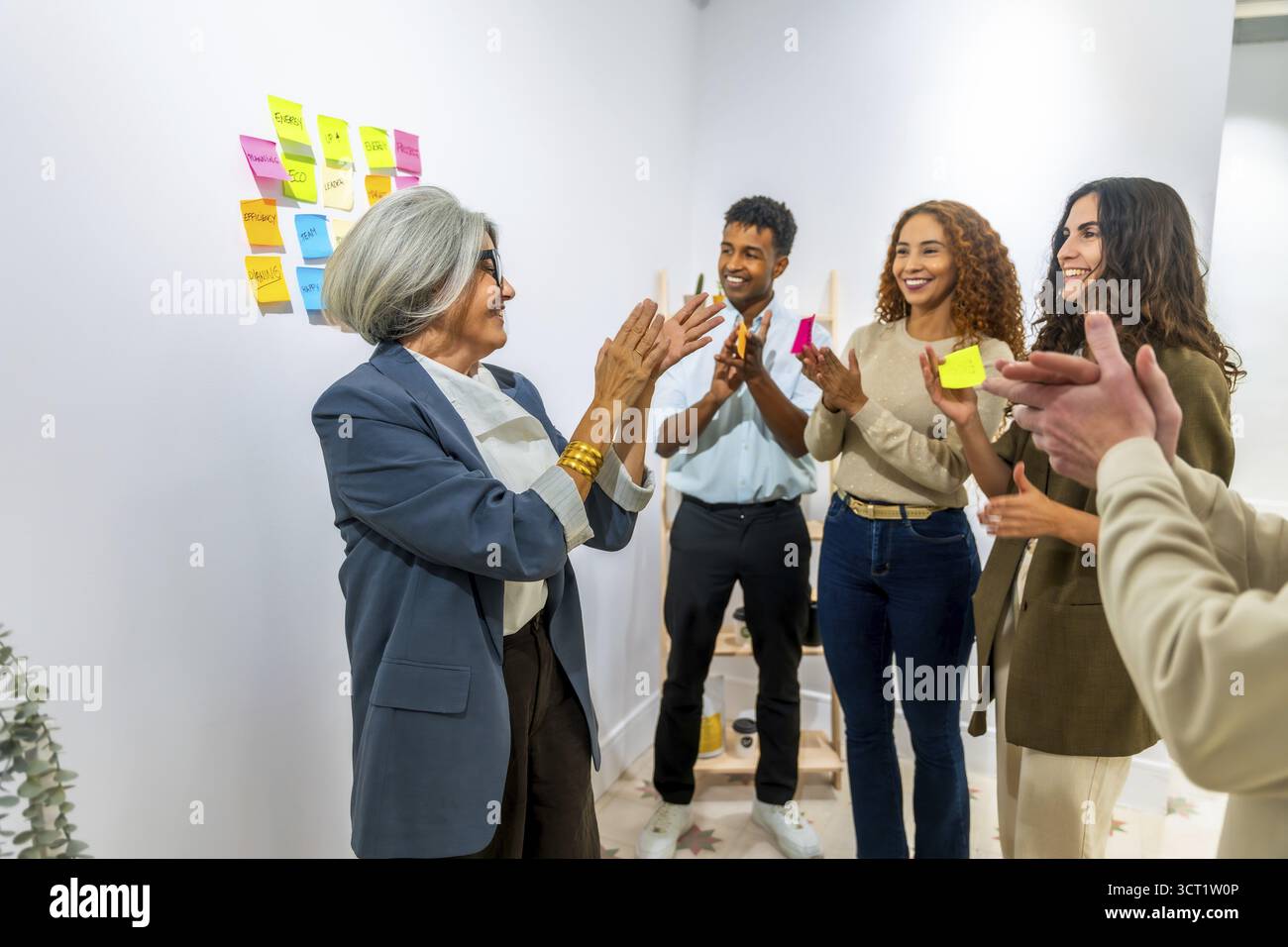 Diverse business people clapping hands in an office meeting room ...