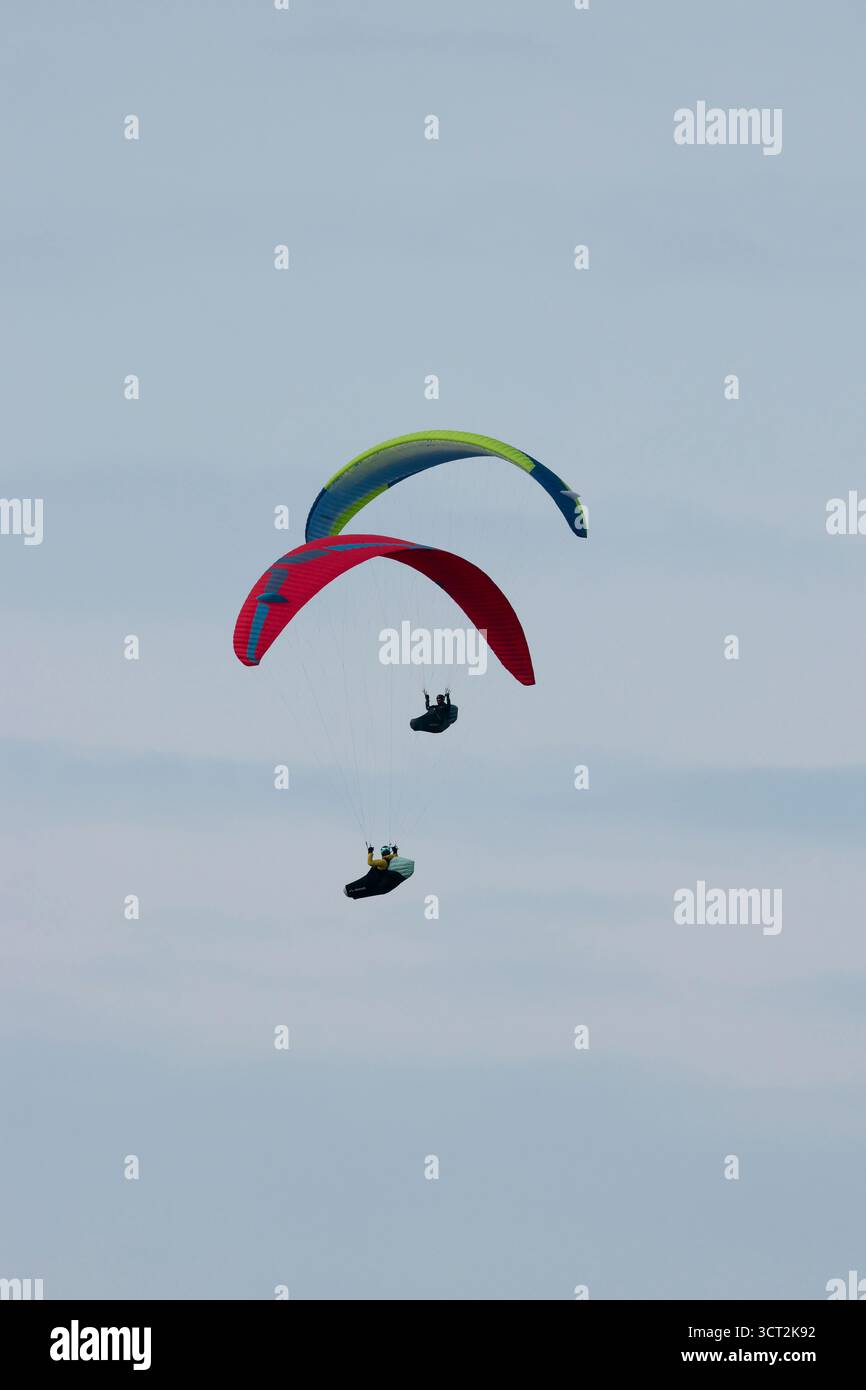 Paragliders pilot sit in pod suspended below fabric wing gliding in ...