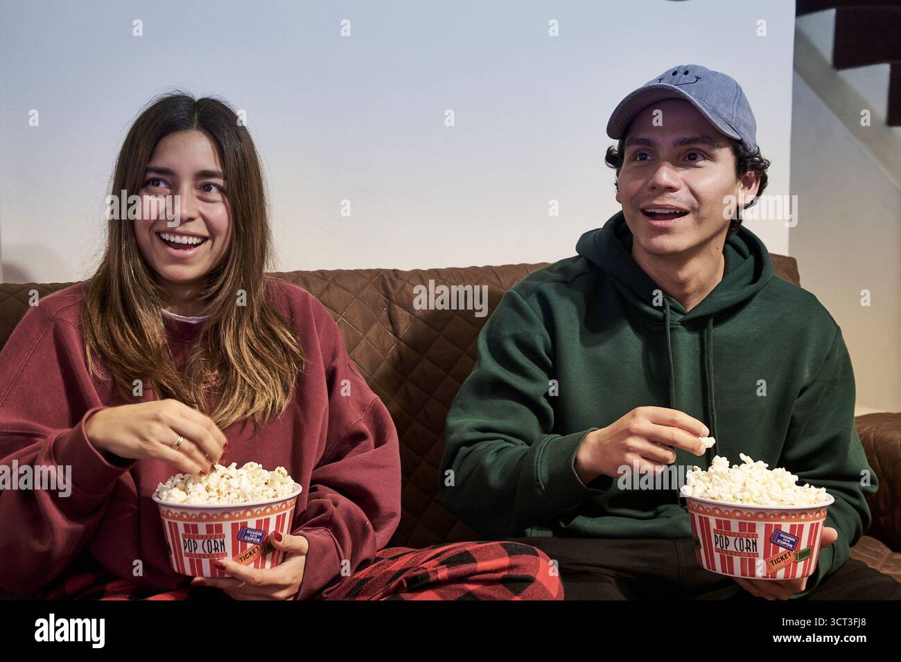 A very entertaining couple eating popcorn while watching a movie at ...