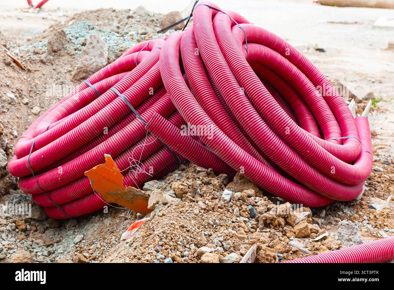 Red corrugated hoses for communications, rolled into a roll and lying ...