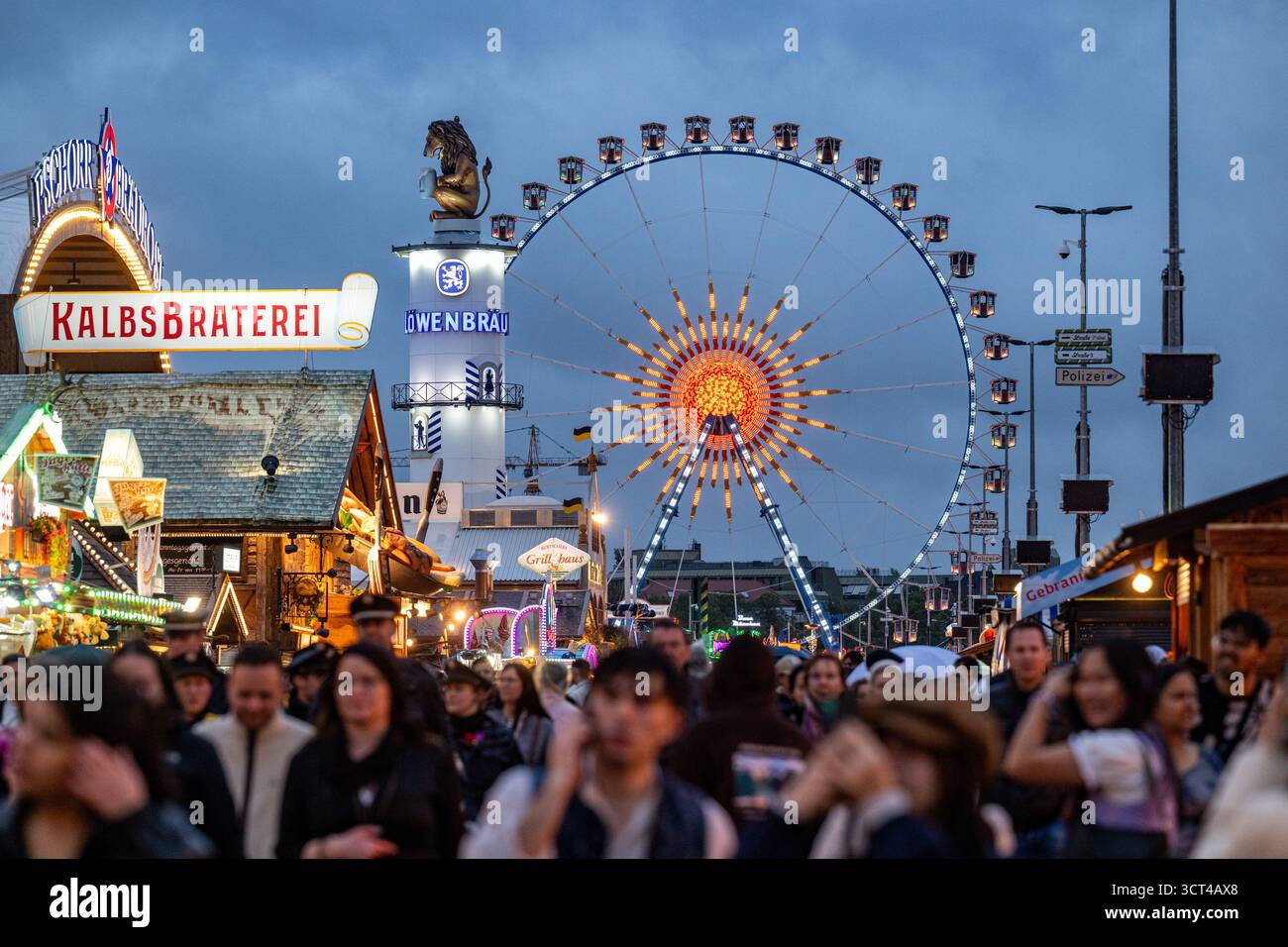 04 October 2025, Bavaria, Munich: Visitors to the Oktoberfest walk ...
