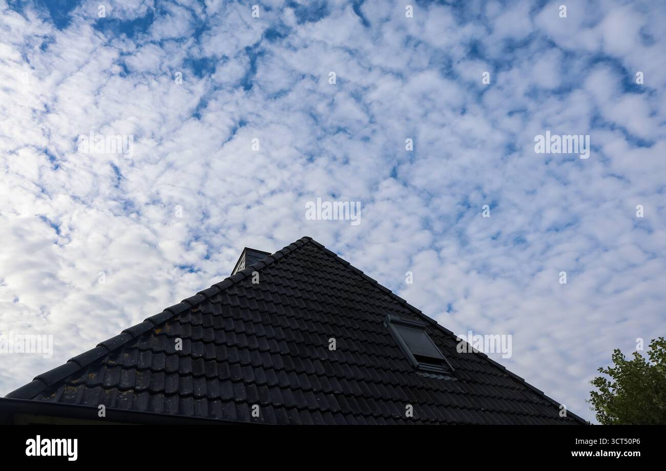 House roof with dark tiles and a skylight creating a striking contrast ...