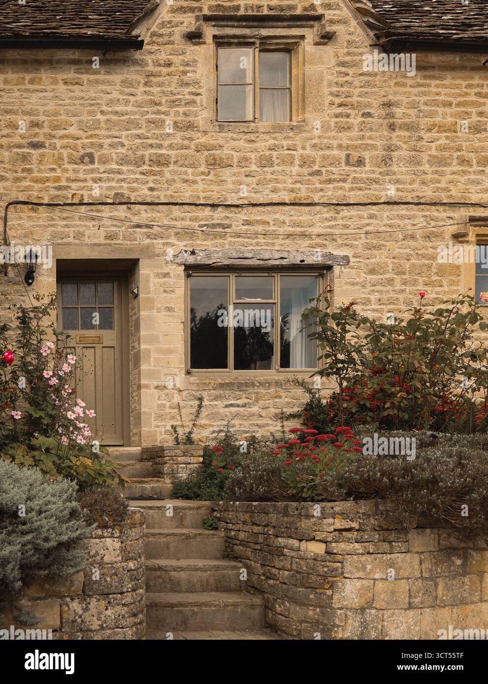 Traditional English cottage built with rustic yellow stone, featuring a ...