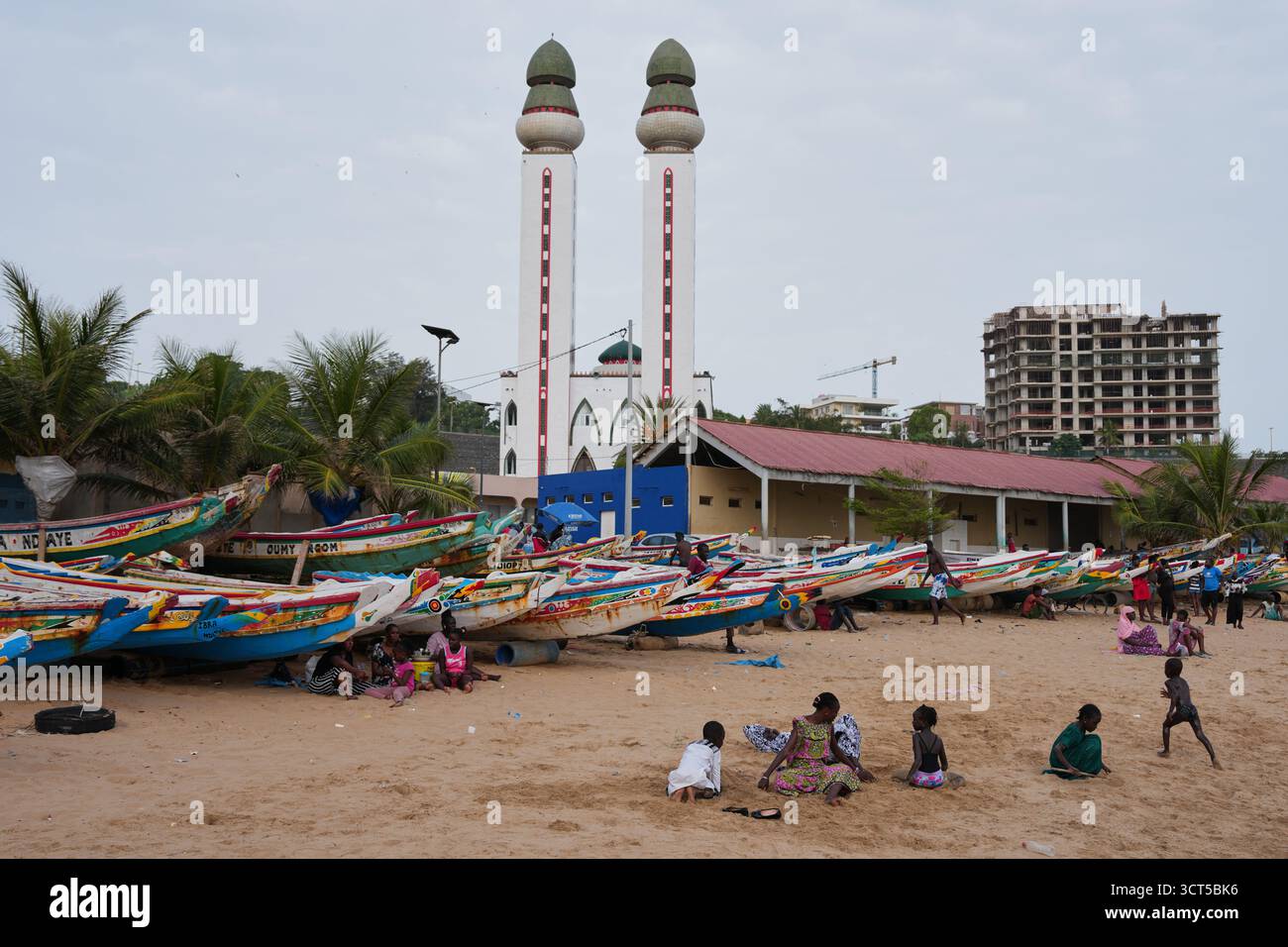 People relax on the beach near traditional fishing boats along the ...