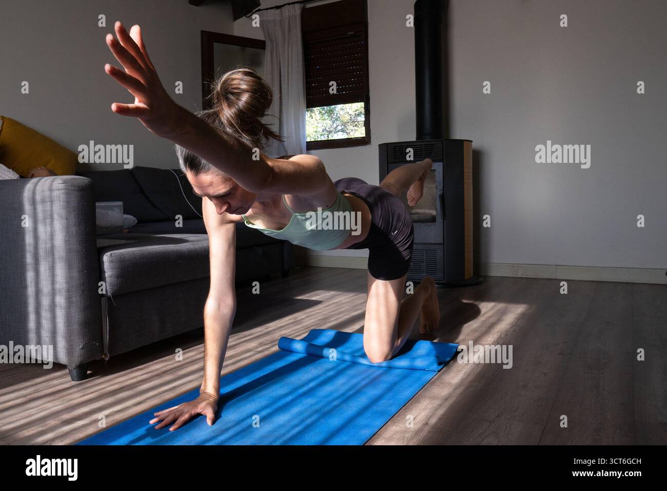 Woman performing balancing table yoga pose on exercise mat in living ...
