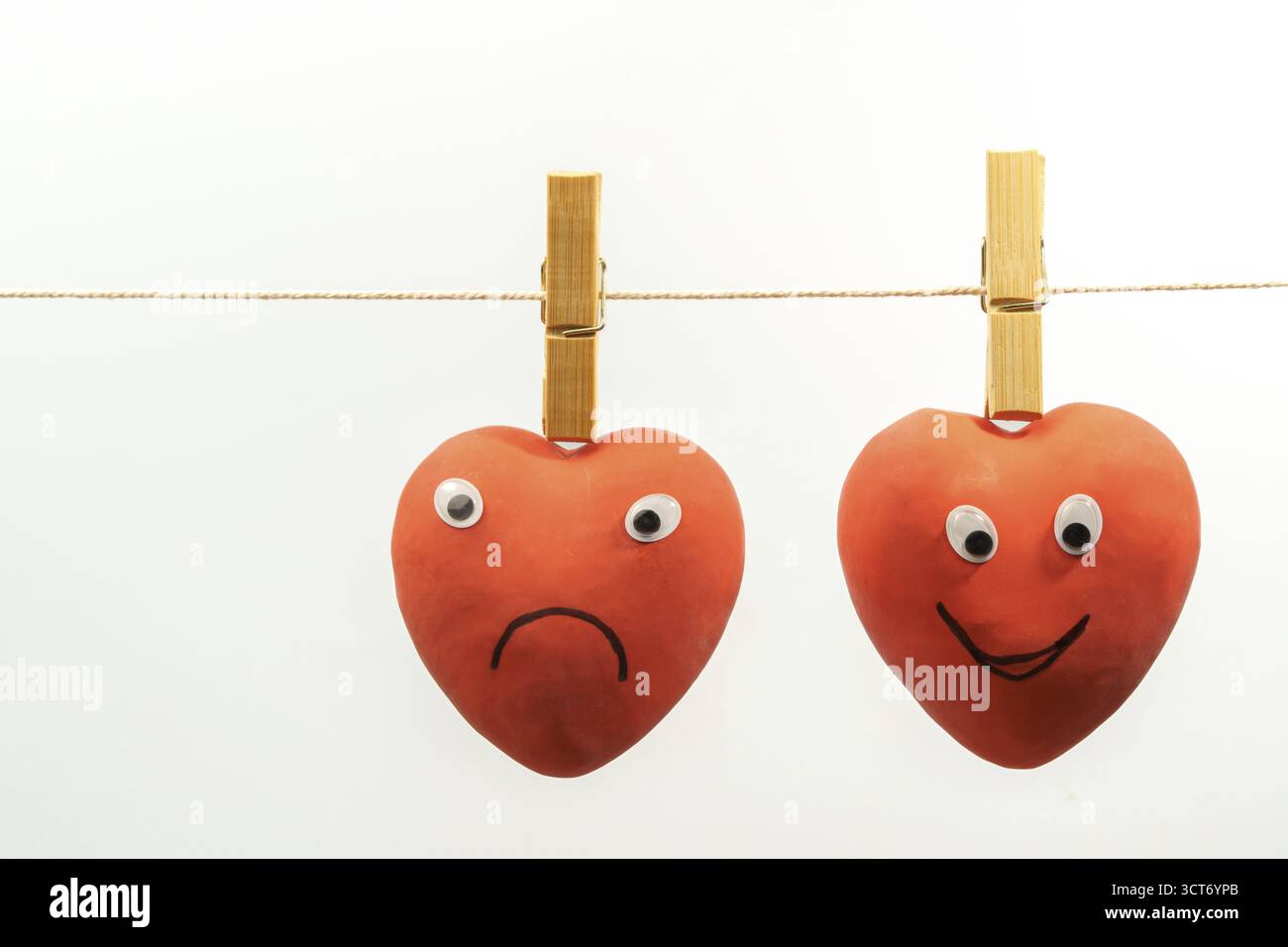 Hearts with happy and sad expressions hanging on a rope, representing ...